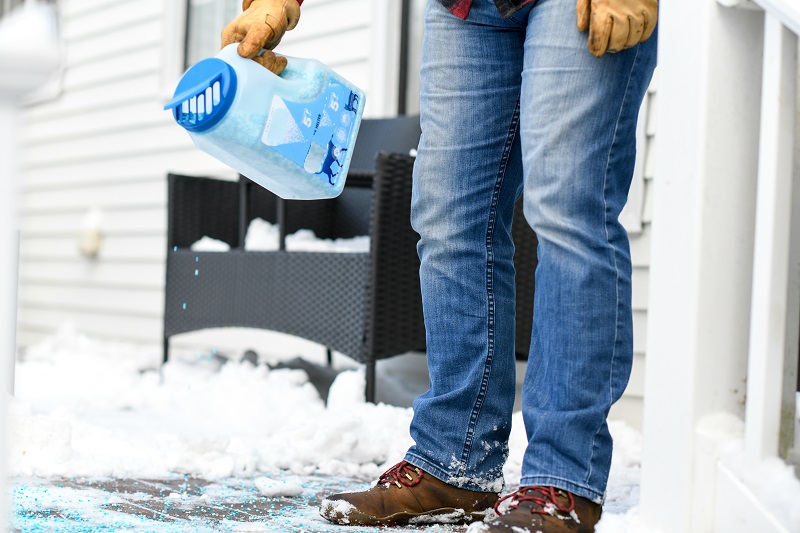 Man pouring salt onto the sidewalk to prevent ice and snow