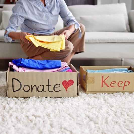 Woman decluttering her home and organizing clothes into boxes, one ...