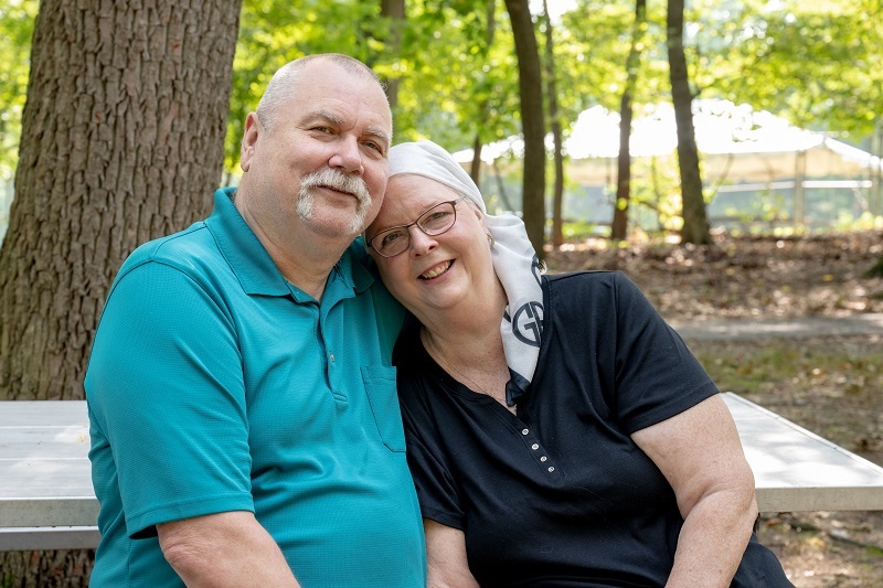 Kim Mosko and her husband sitting close outside and smiling.